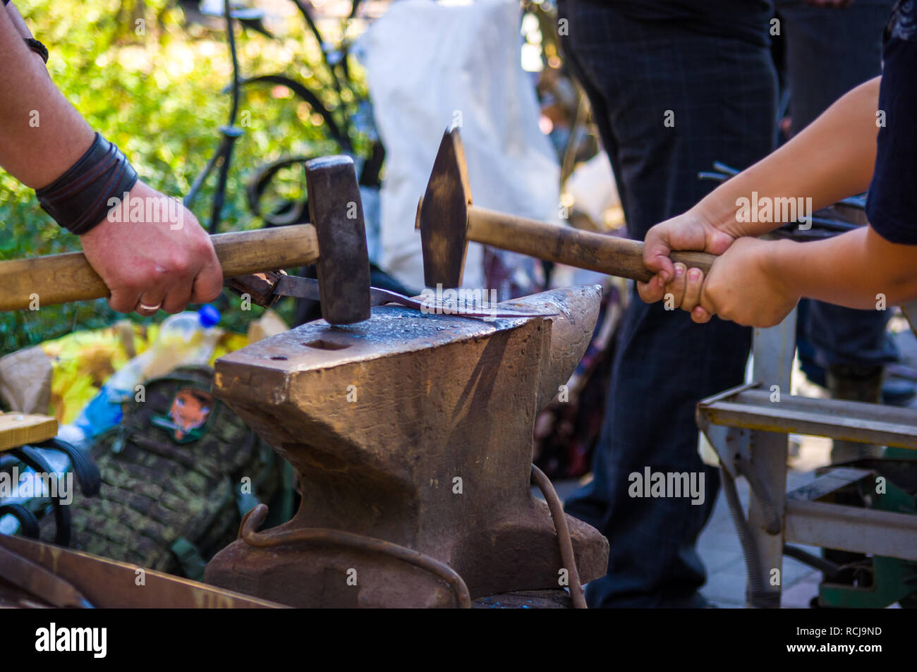 blacksmith performs the forging of hot glowing metal on the anvil ...