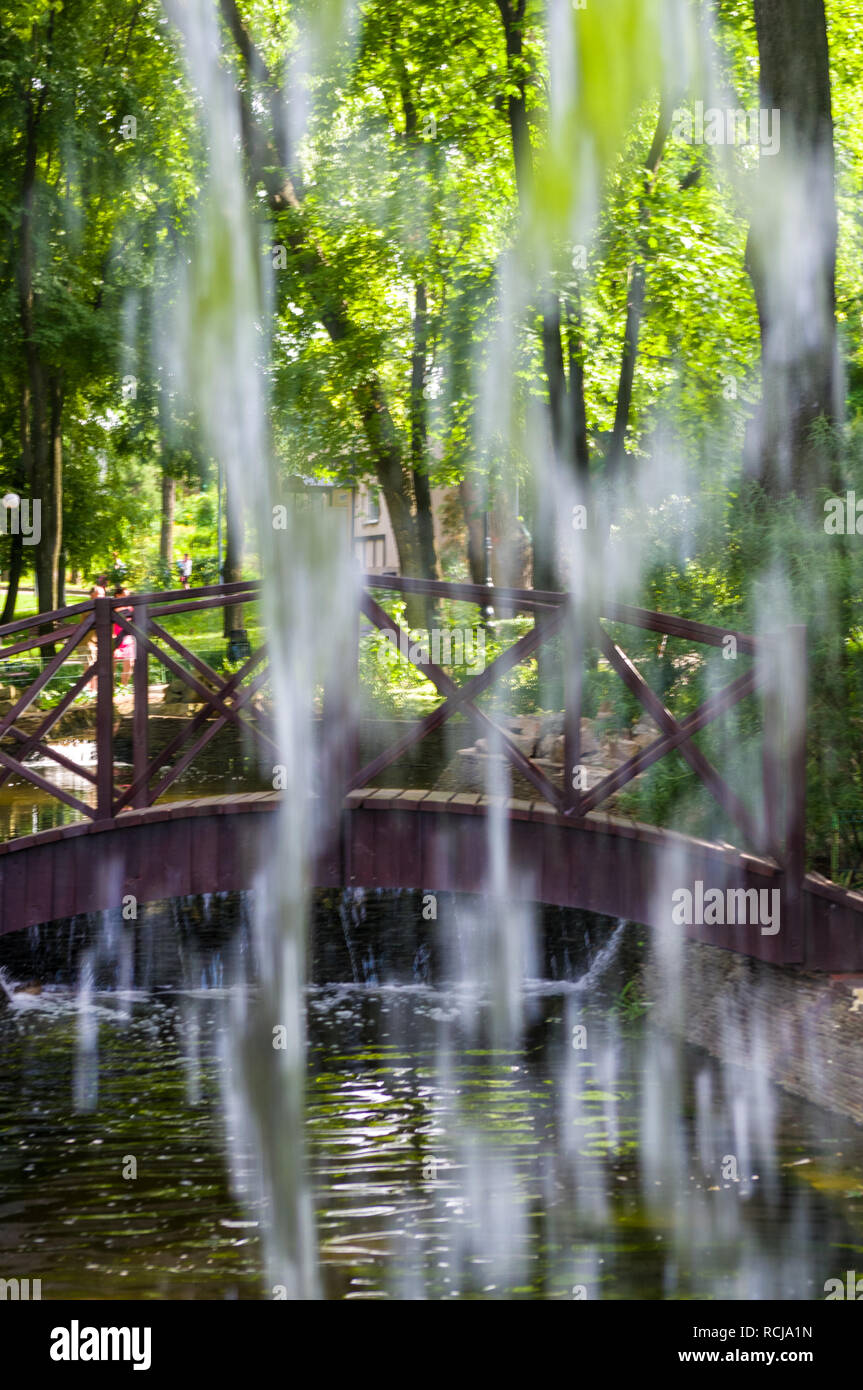 transparent falling water vertical flows against a blue sky and green ...