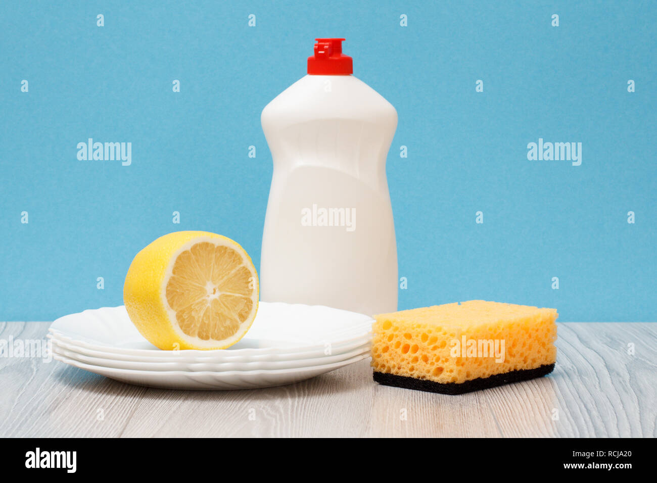 Plastic bottle of dishwashing liquid, clean plates, lemon and sponge on ...