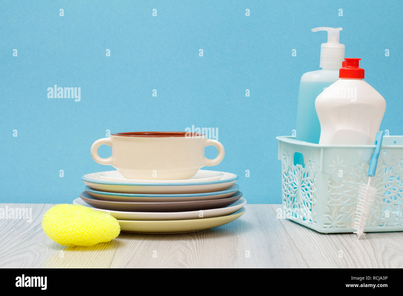 Plastic bottles of dishwashing liquid, glass and tile cleaner in basket ...