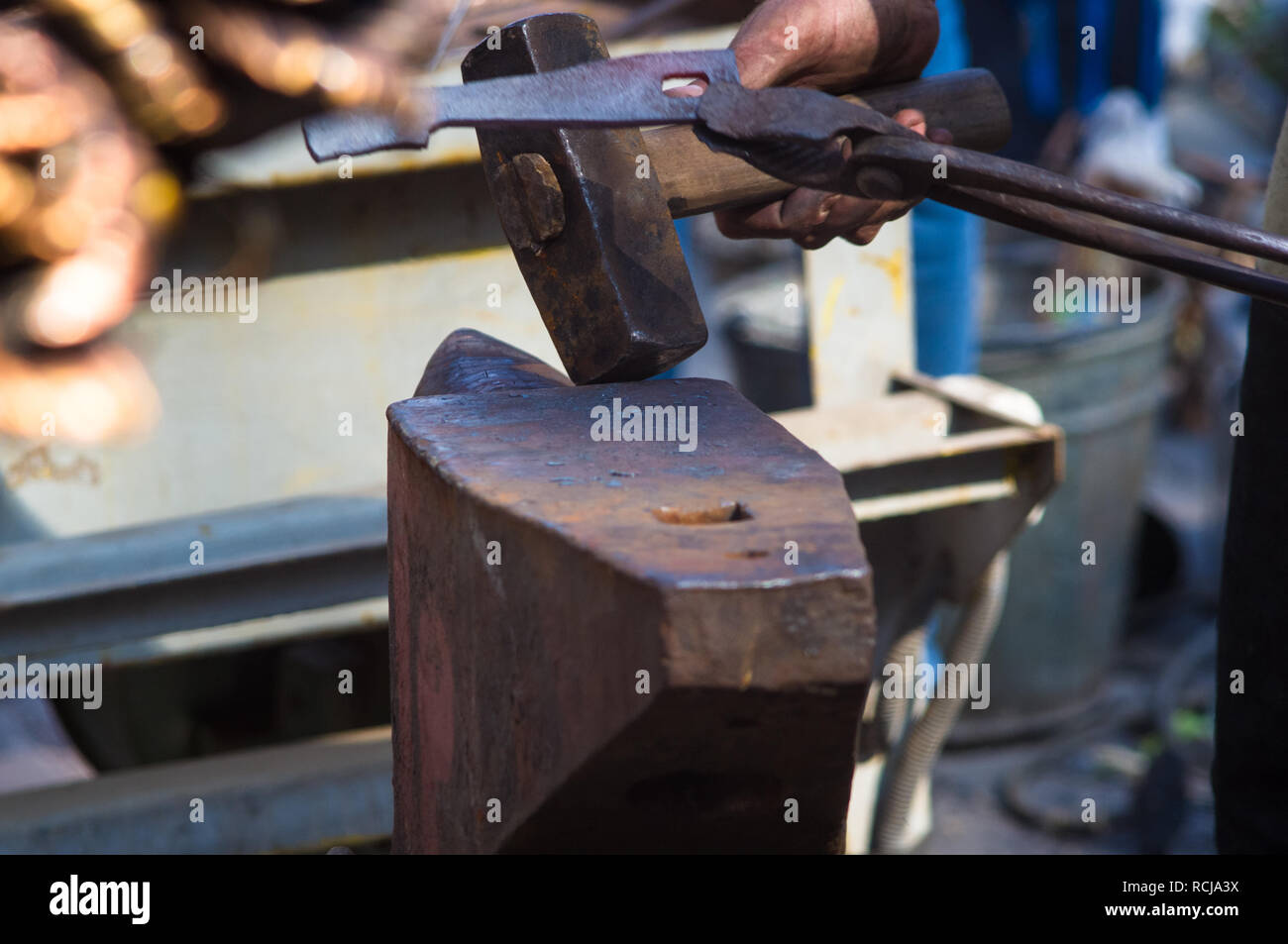 blacksmith performs the forging of hot glowing metal on the anvil ...