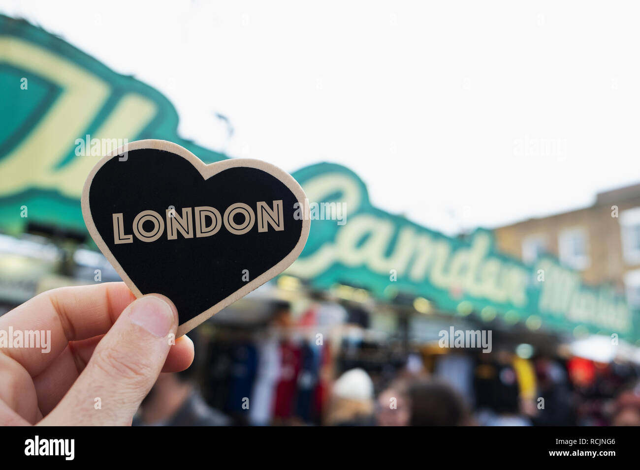 closeup of a caucasian man holding a black heart with the word london ...
