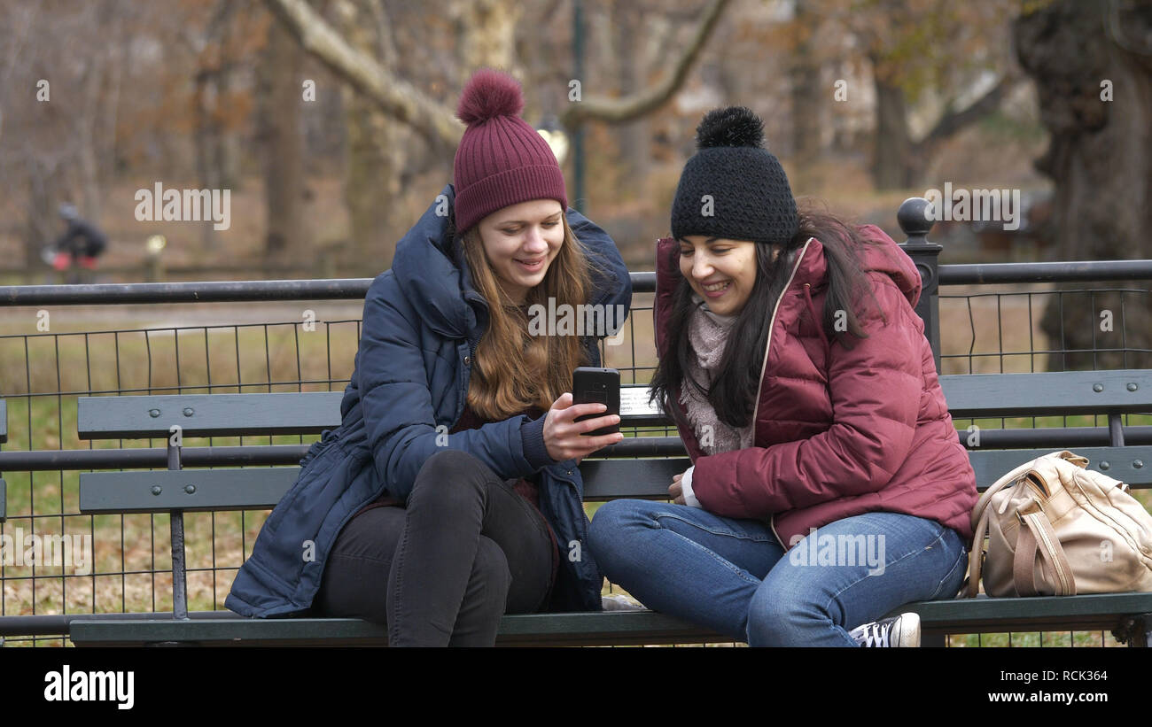 Two friends check the photos on their cell phone Stock Photo - Alamy