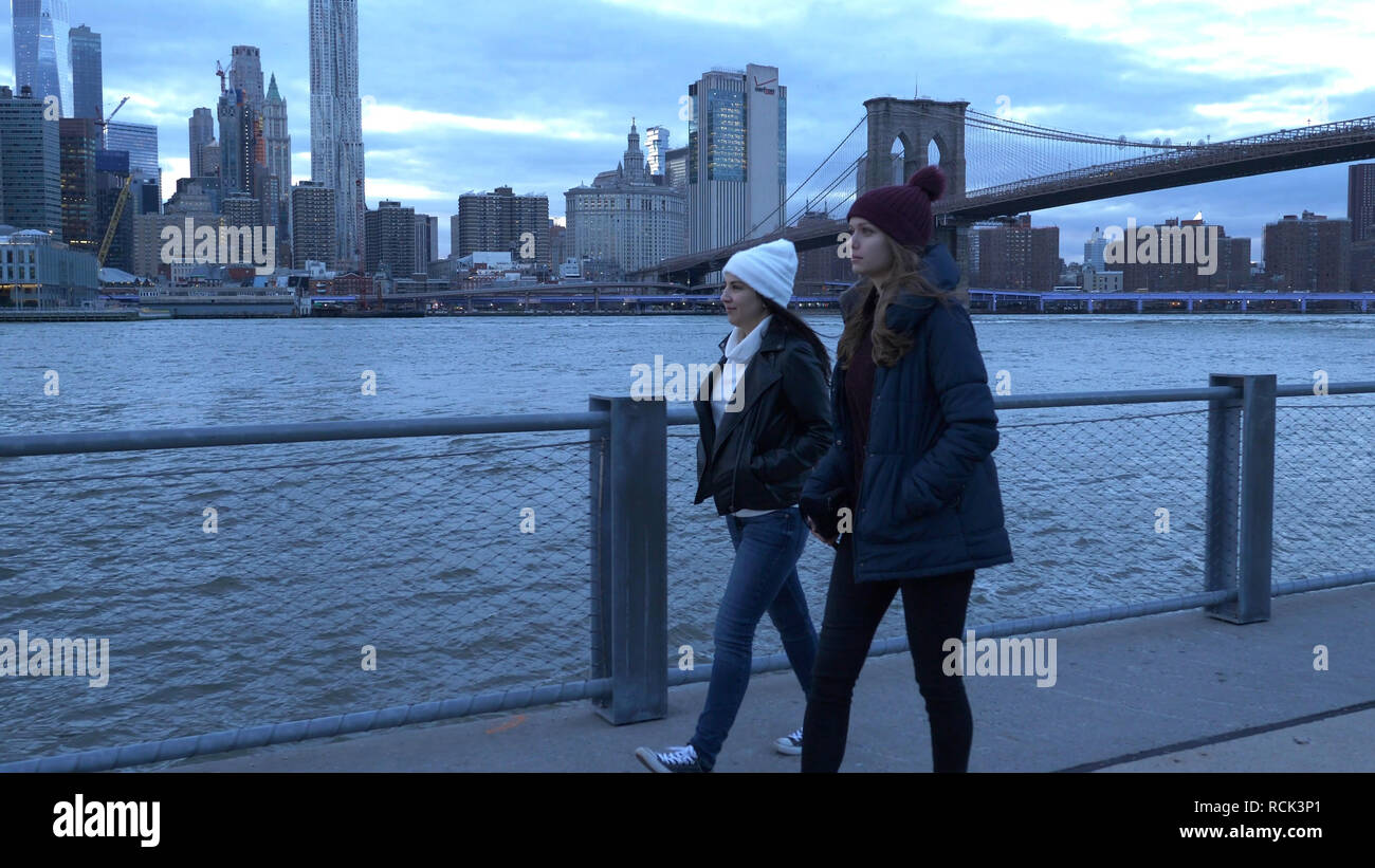 Two friends walk along the amazing skyline of Manhattan in the evening ...
