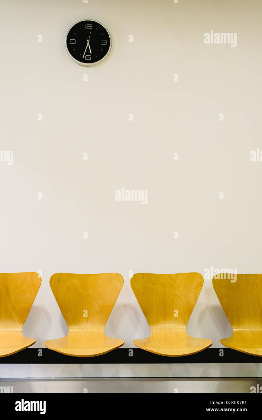 Waiting room with empty wooden chairs and wall clock, waiting concept ...