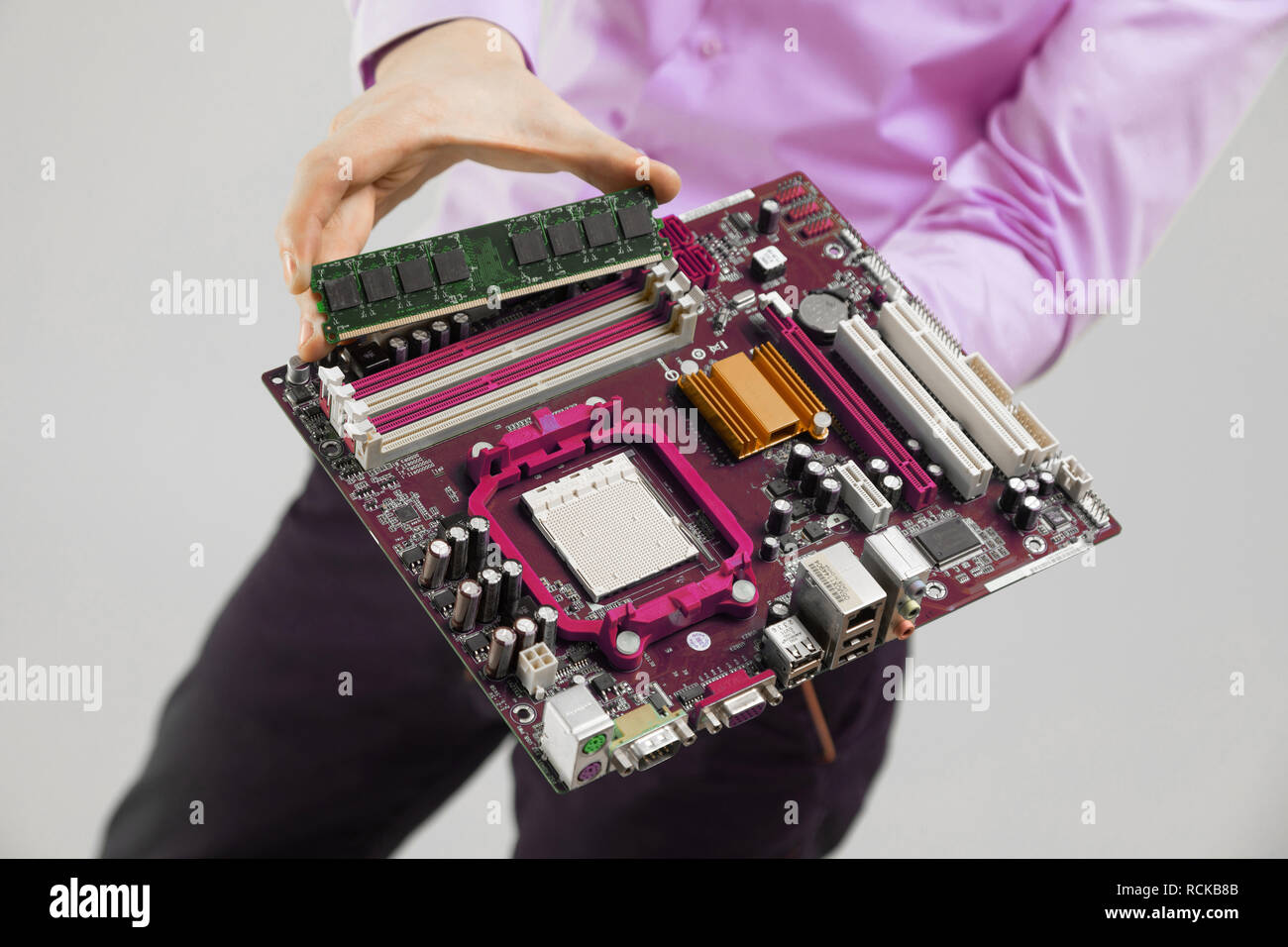 RAM and motherboard in men's hands close-up isolated on light ...