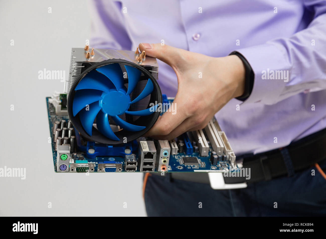 Cooler and motherboard in men's hands close-up isolated on light ...