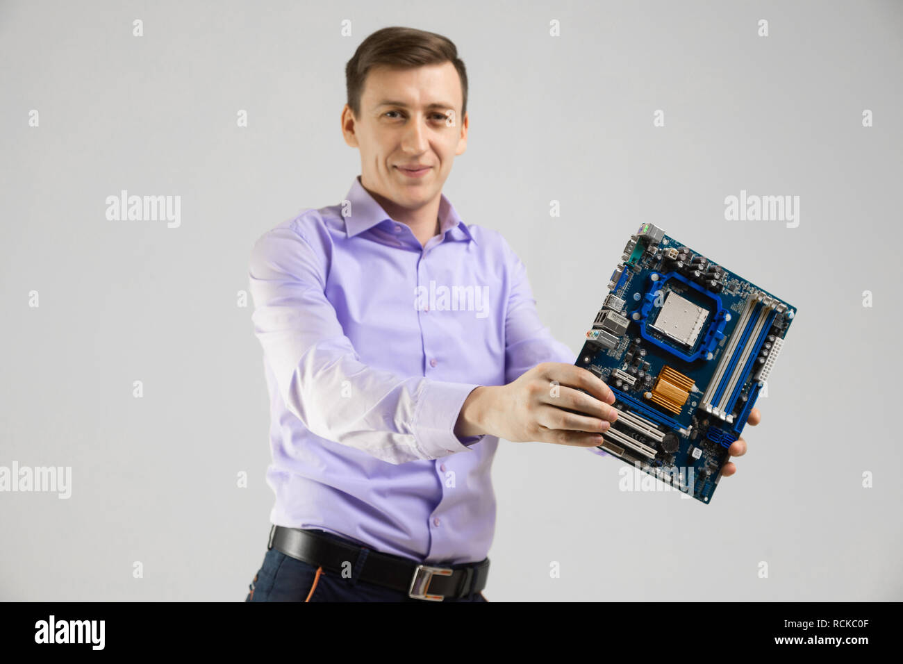 young man with motherboard in his hands is isolated on light background ...