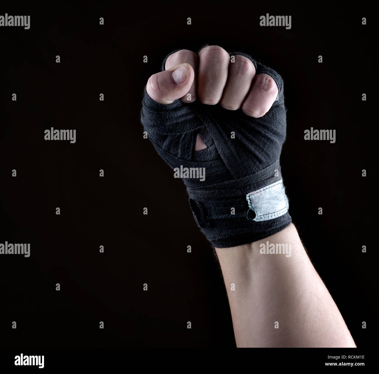 male hand is wrapped in a black sports textile bandage on a black ...