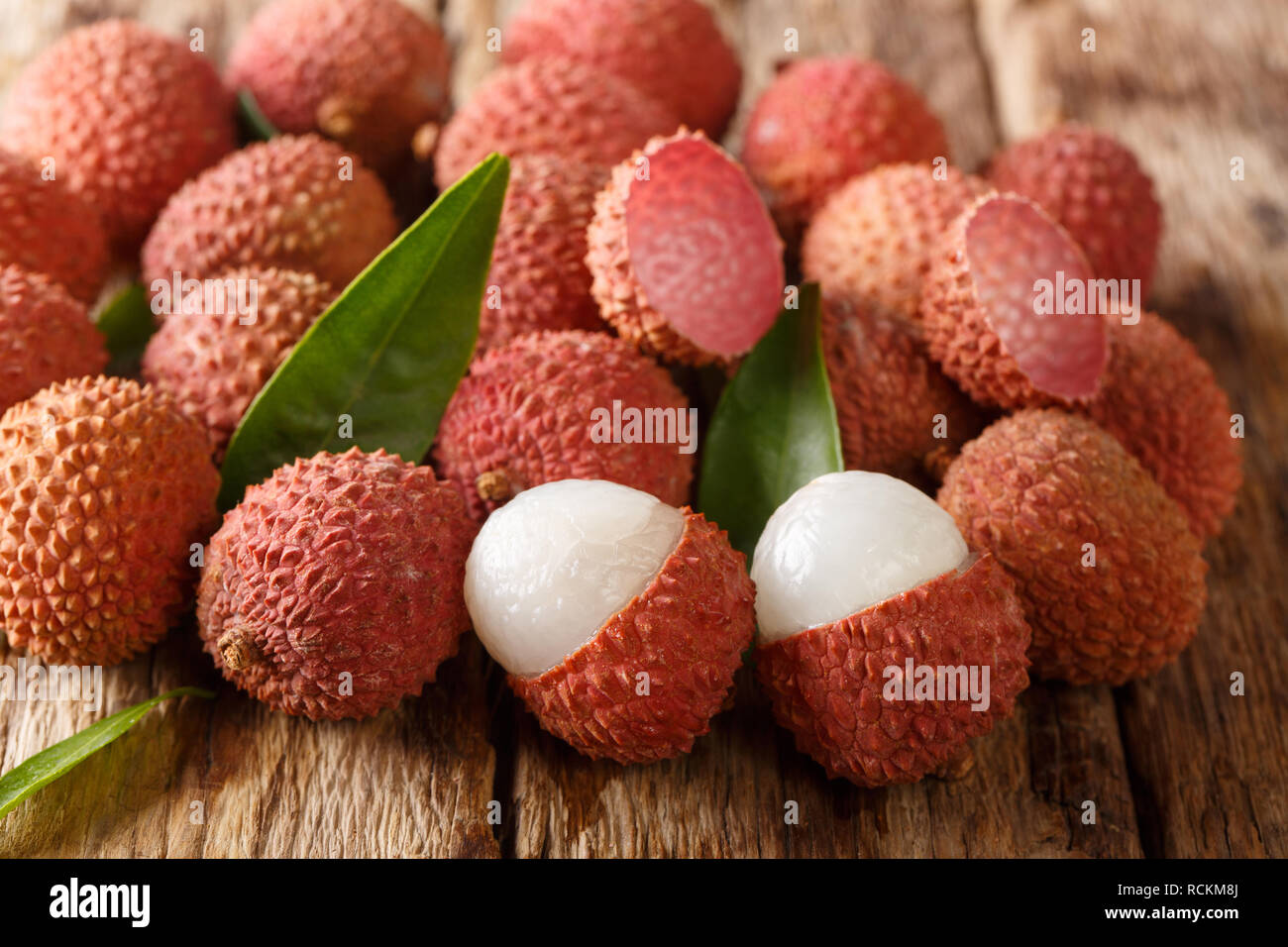 Fresh lychee and peeled showing the red skin and white flesh with green ...