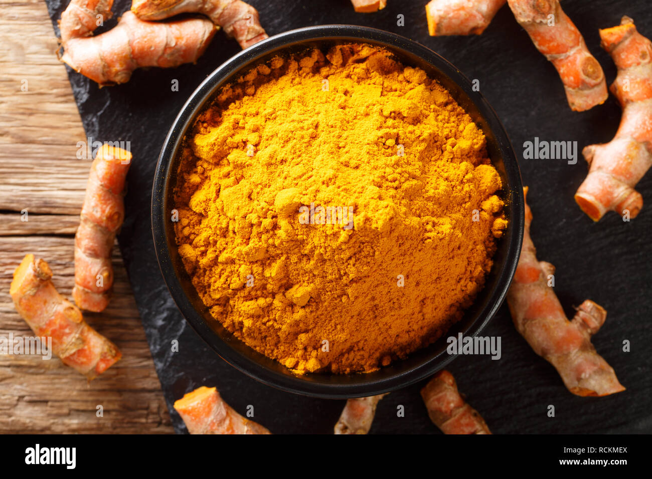 Fresh turmeric spice in a bowl and root close-up on the table ...