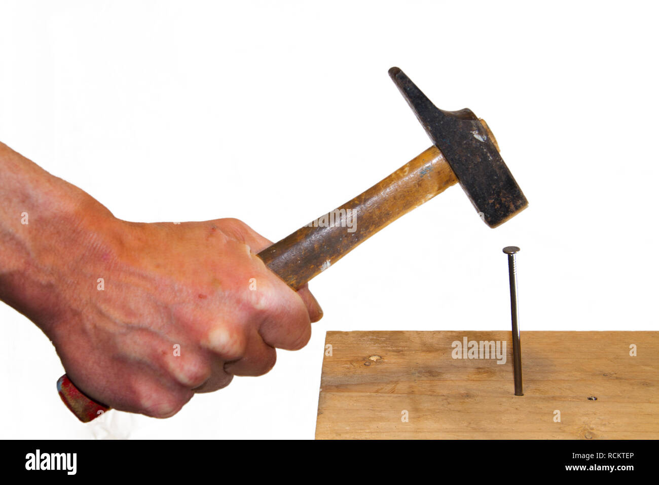 Hand holding hammer with wooden handle driving nail into wood, isolated ...
