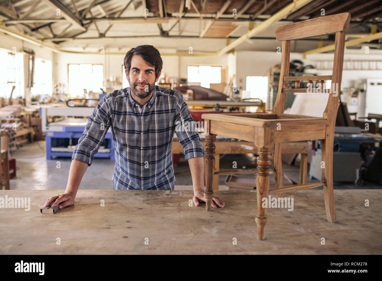 Smiling furniture maker sanding a chair in his workshop Stock Photo - Alamy