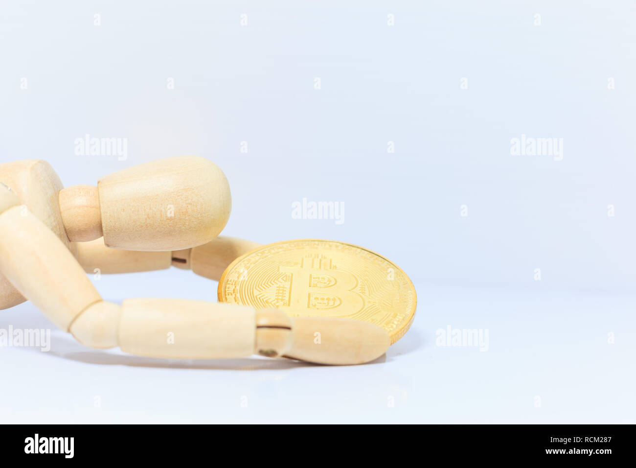 wooden robot model stops falling Bitcoin cryptocurrency token on white ...