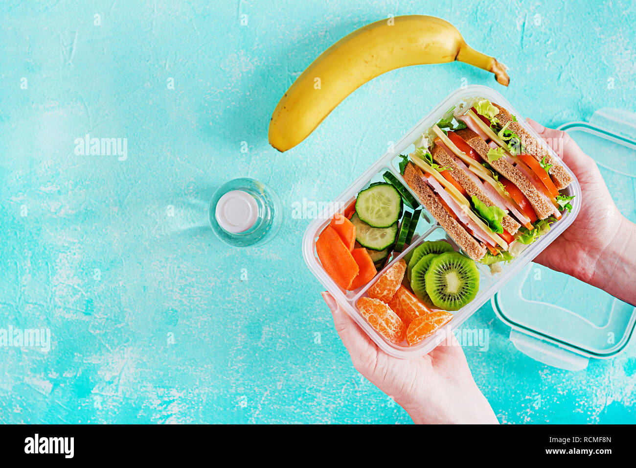 Lunchbox in hands. School lunch box with sandwich, vegetables, water ...