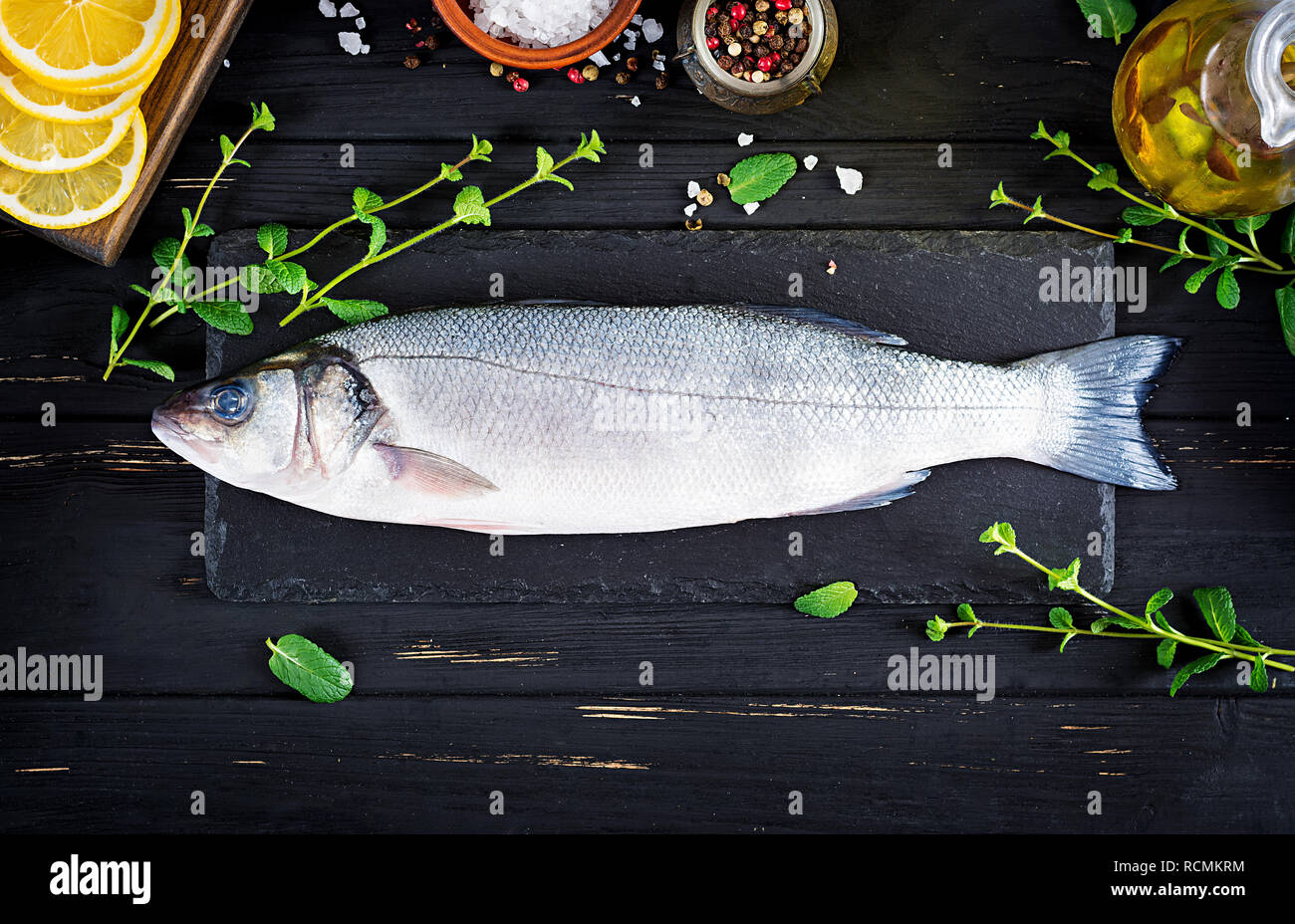 Raw fish. Sea bass on slate blackboard. Ingredients for cooking, grill ...