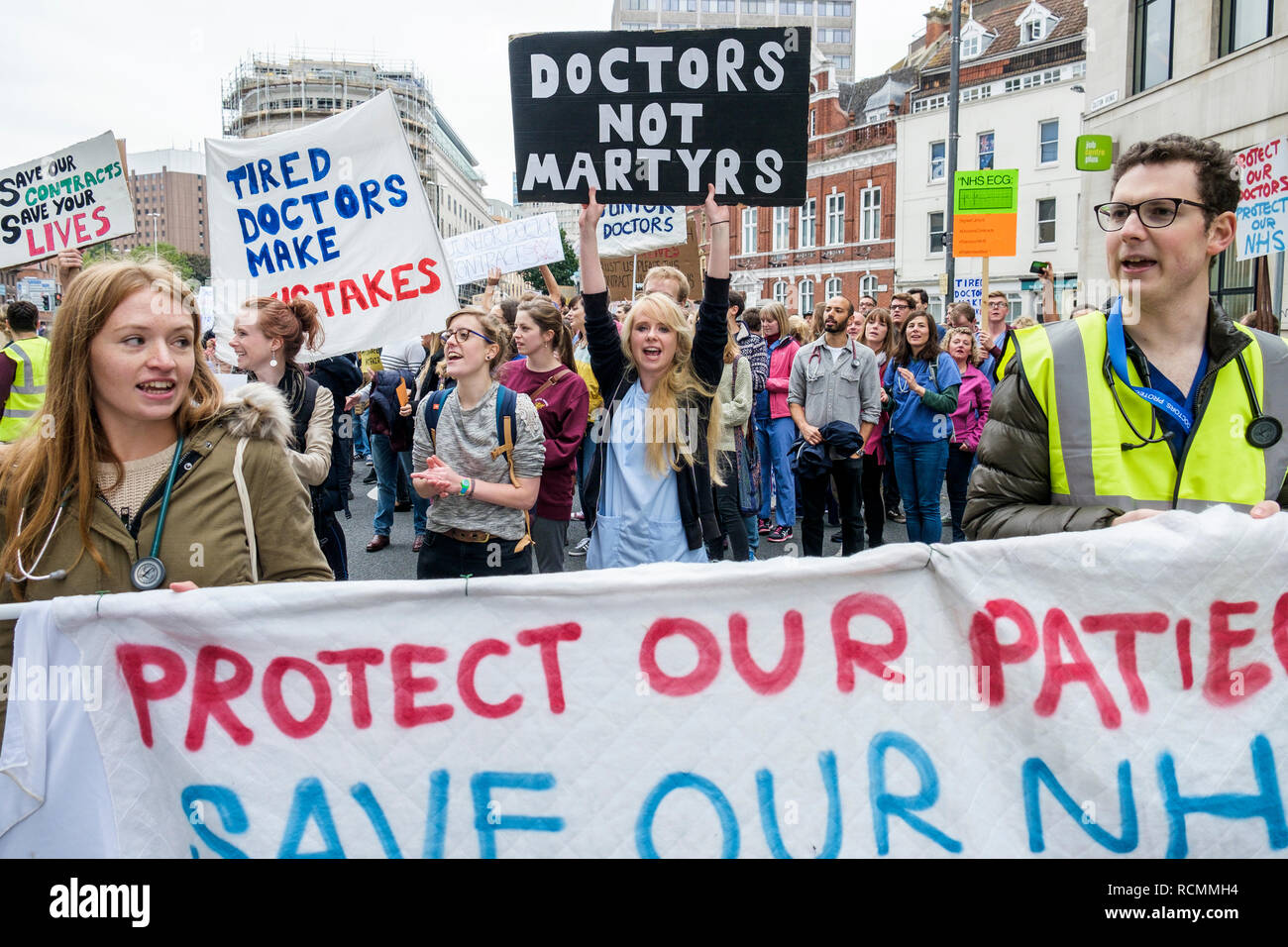 NHS staff and members of the public are pictured carrying placards and ...