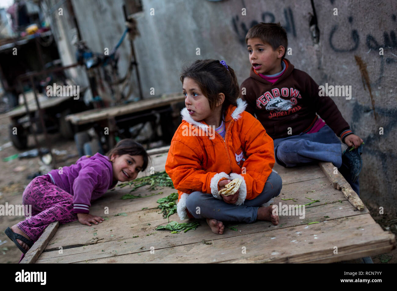 Palestinian refugee children seen playing on a cart in front of their ...
