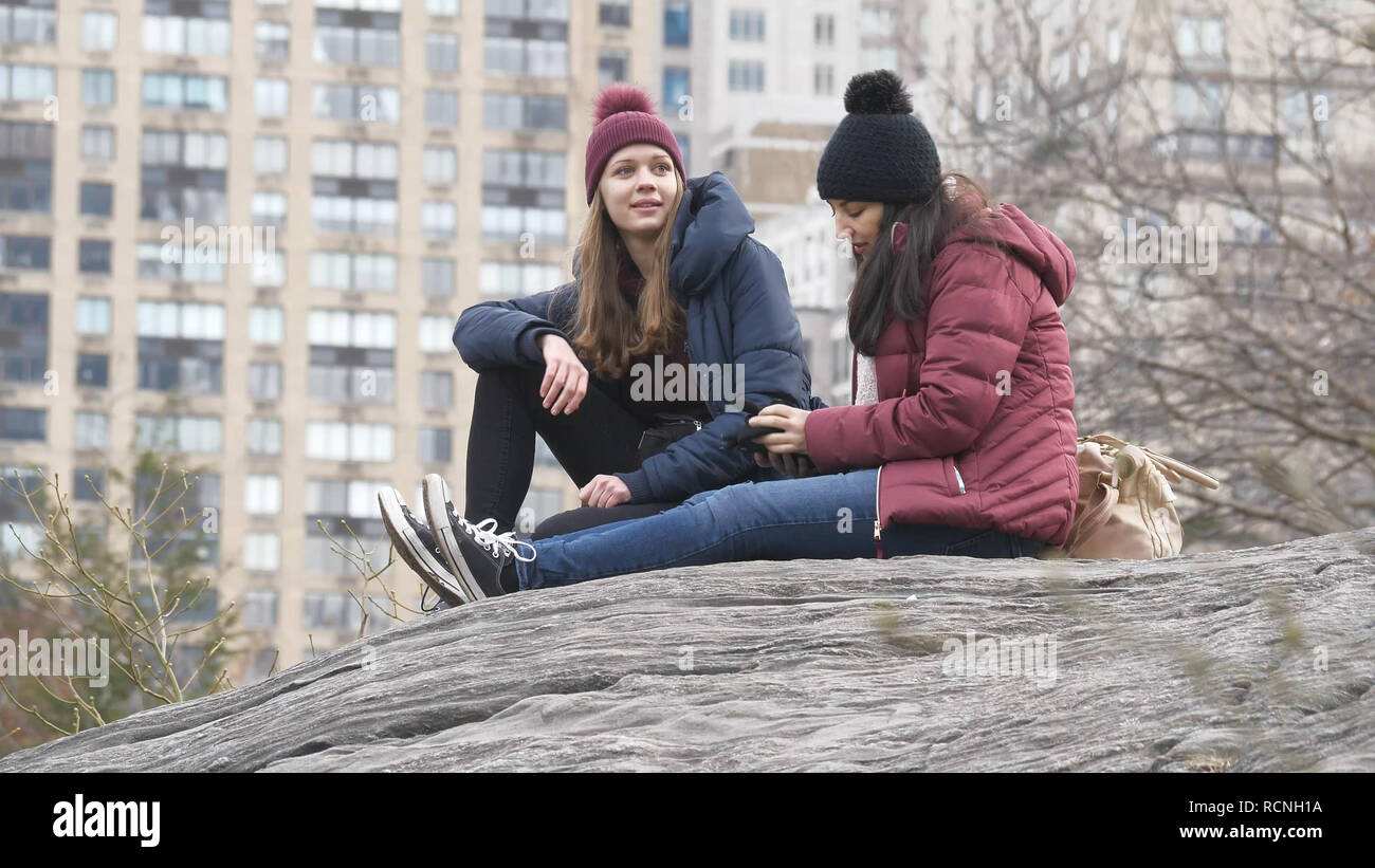 Two girls sit on a rock in Central Park New York Stock Photo - Alamy