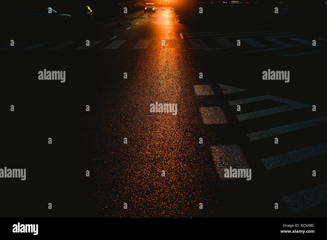 Urban background of a dark street at dusk with cars and traffic marks ...