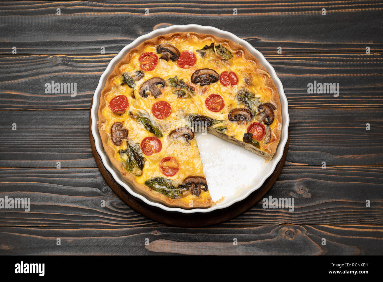 Baked homemade quiche pie in ceramic baking form on concrete background ...