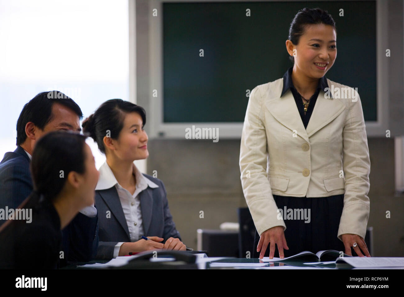 Young adult business woman standing in a boardroom presenting to ...