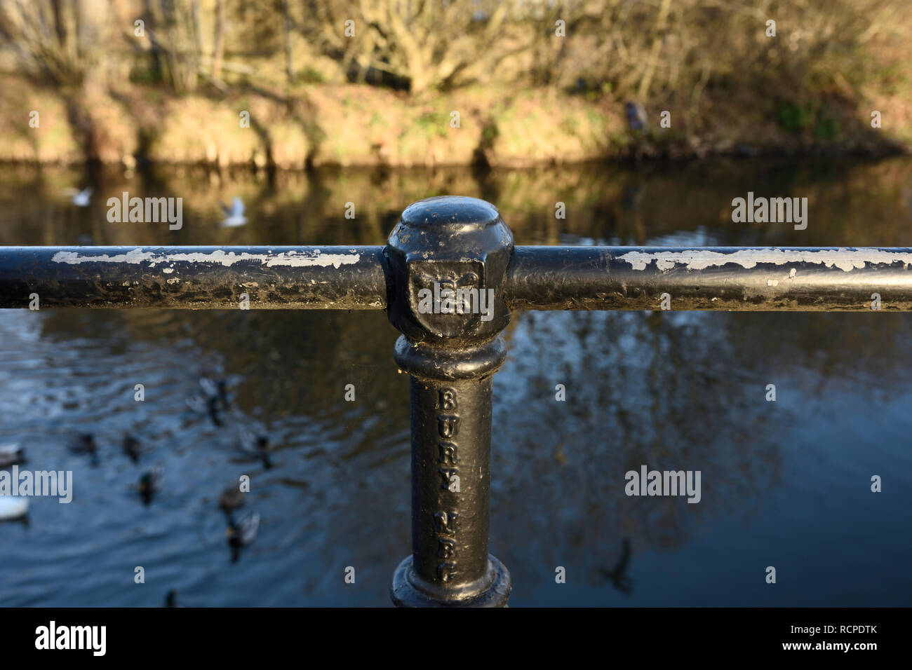 Black Metal handrail and post with blurred river irwell and river bank ...