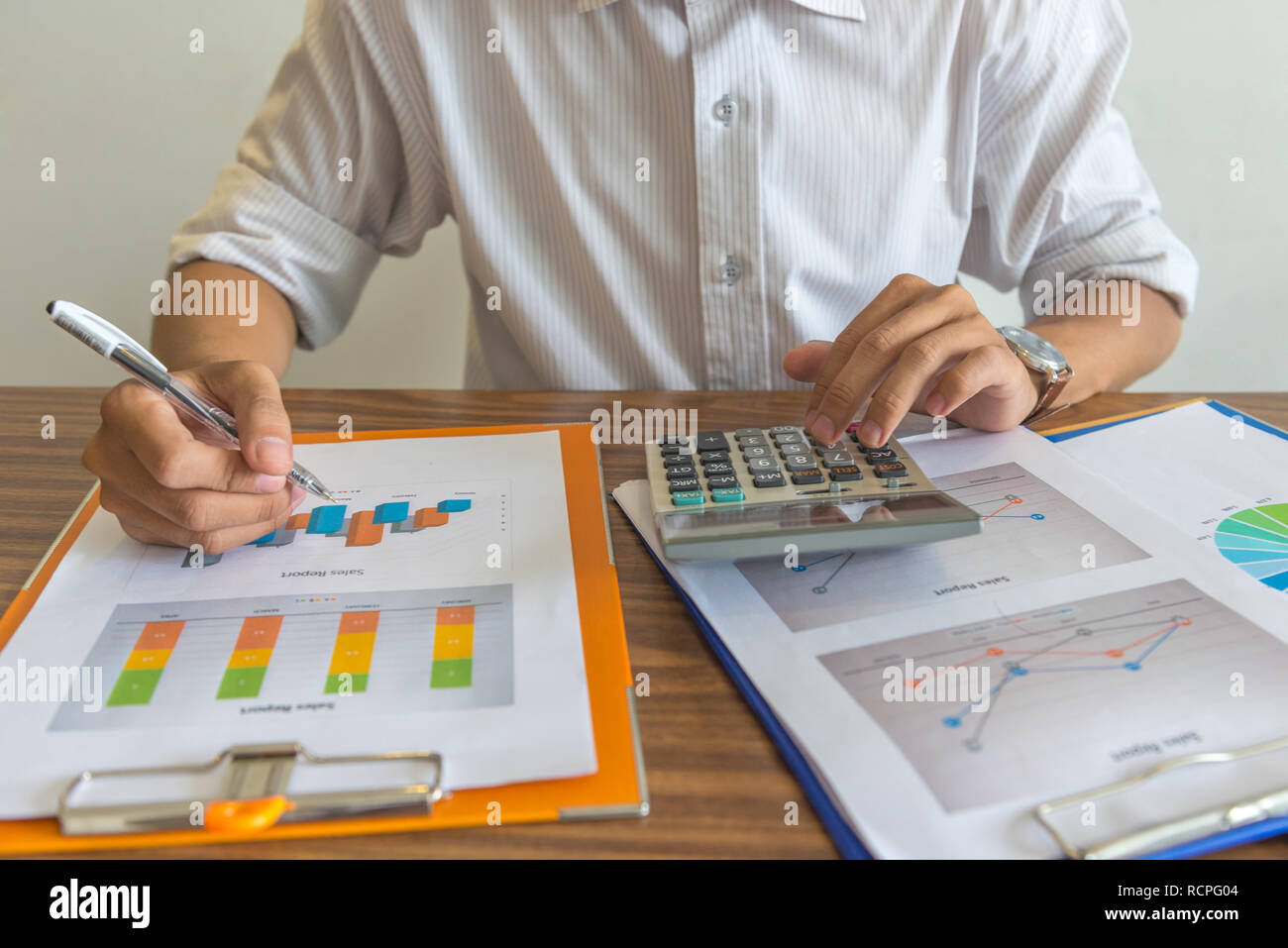 Businessman using calculator to check financial report Stock Photo - Alamy