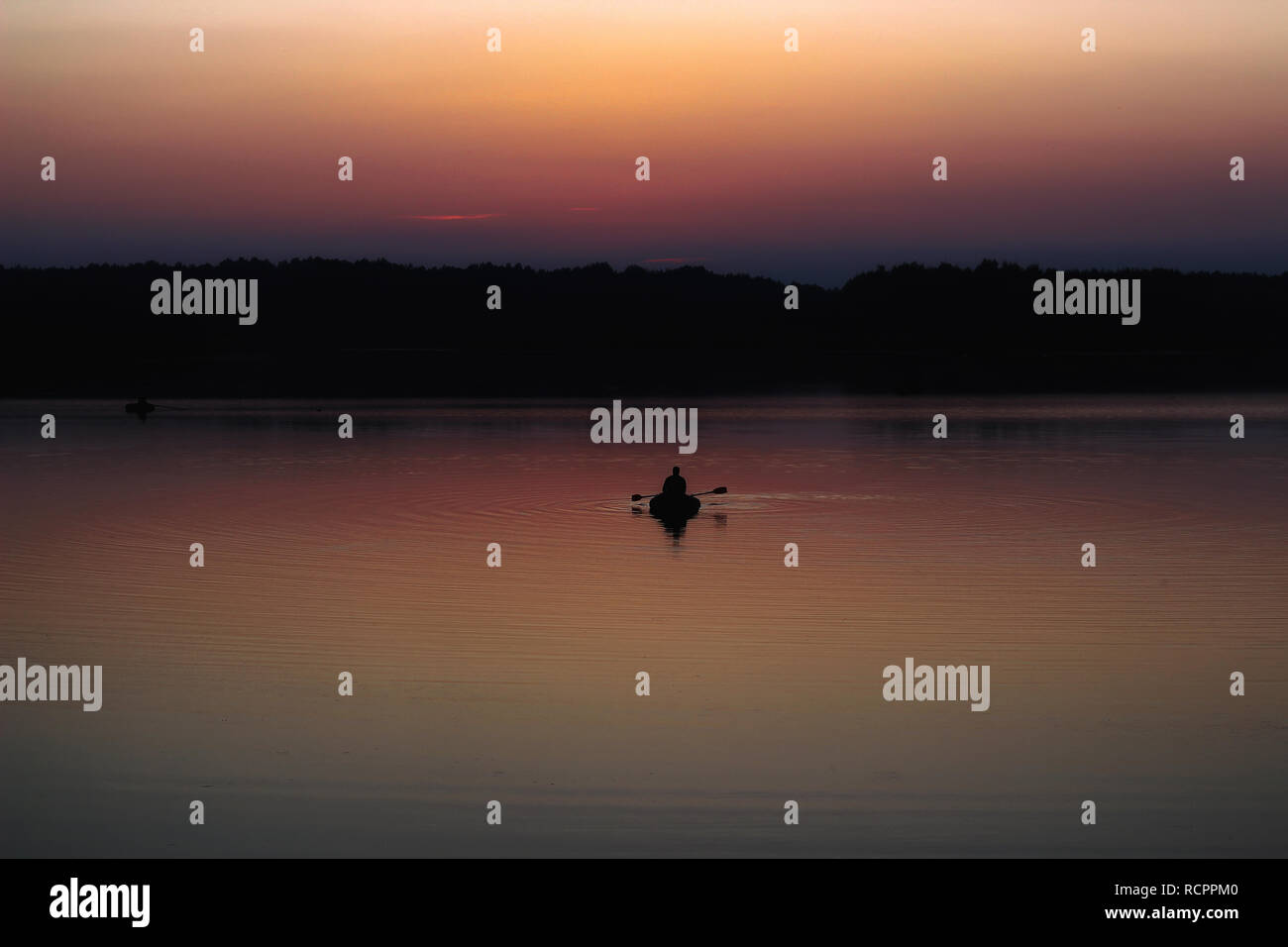 Silhouette of a man which floating on a boat on the sea at sunset time ...