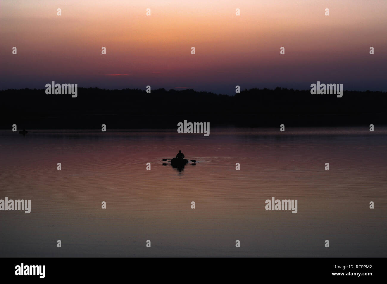 Silhouette of a man which floating on a boat on the sea at sunset time ...