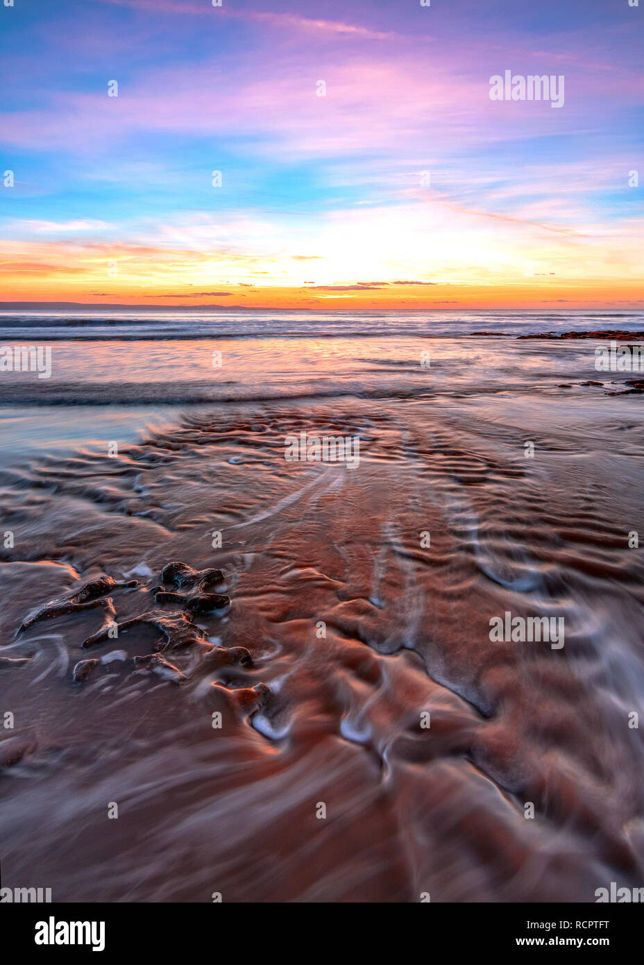 Long Exposure photos of sunset on beach with rocks and blurry sea Stock ...