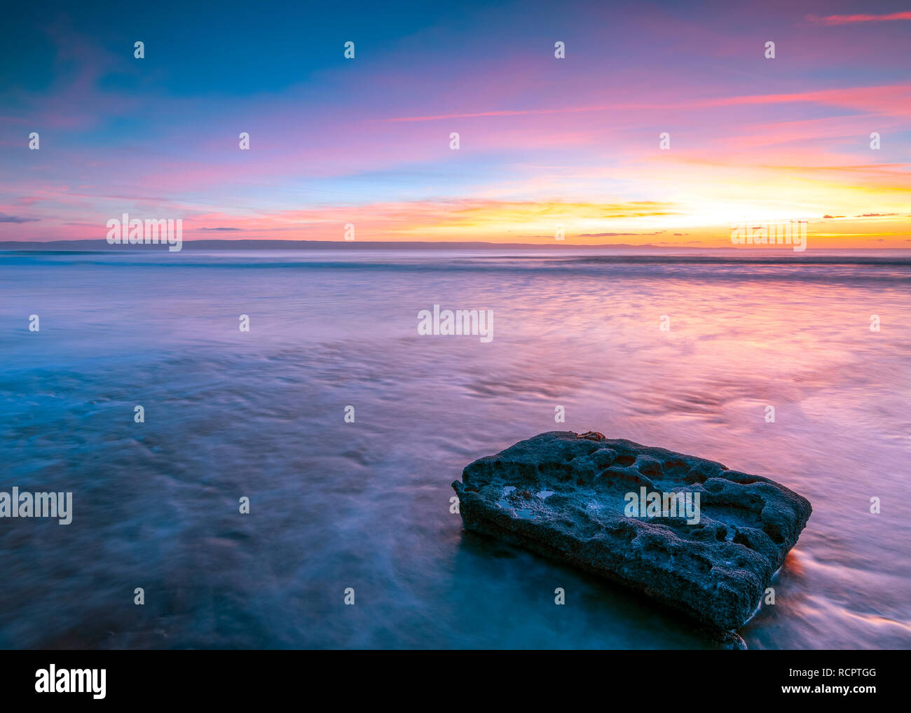 Long Exposure photos of sunset on beach with rocks and blurry sea Stock ...