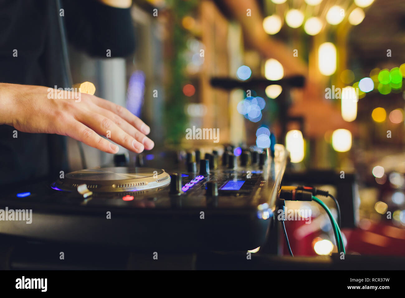 DJ playing music at mixer closeup and mixes the track in the nightclub ...