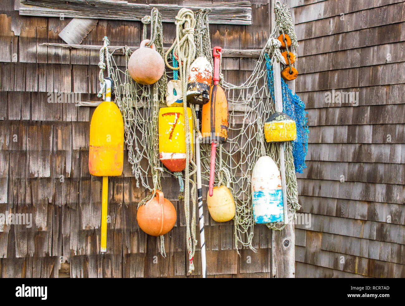 colorful lobster buoys and fishing net hanging on the wall of a ...