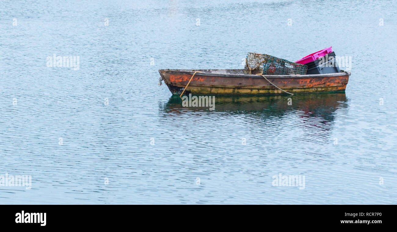solitary rusty rowboat floating in the ocean carrying a lobster trap ...