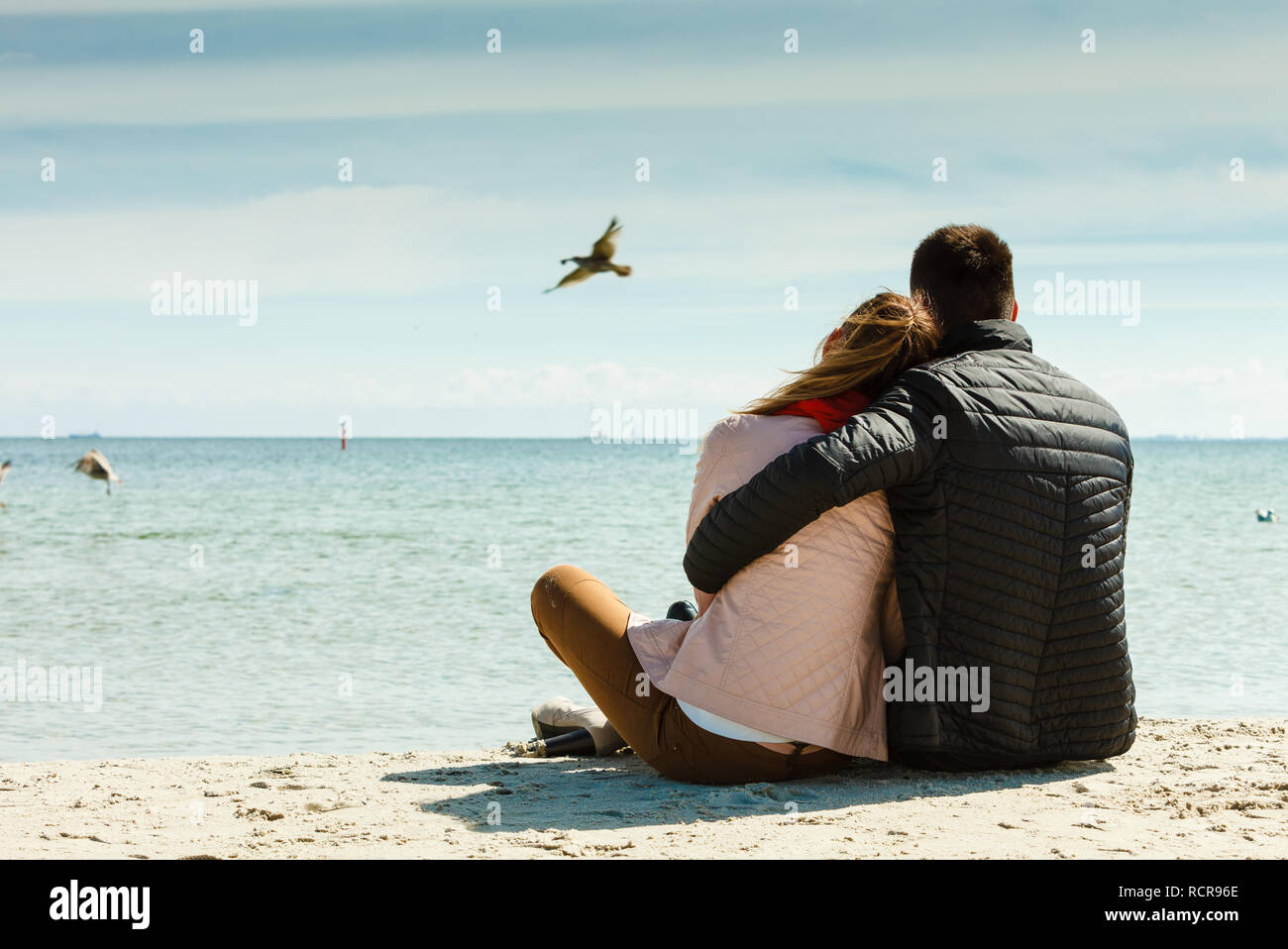loving couple spending leisure time together at beach hugging rear view ...