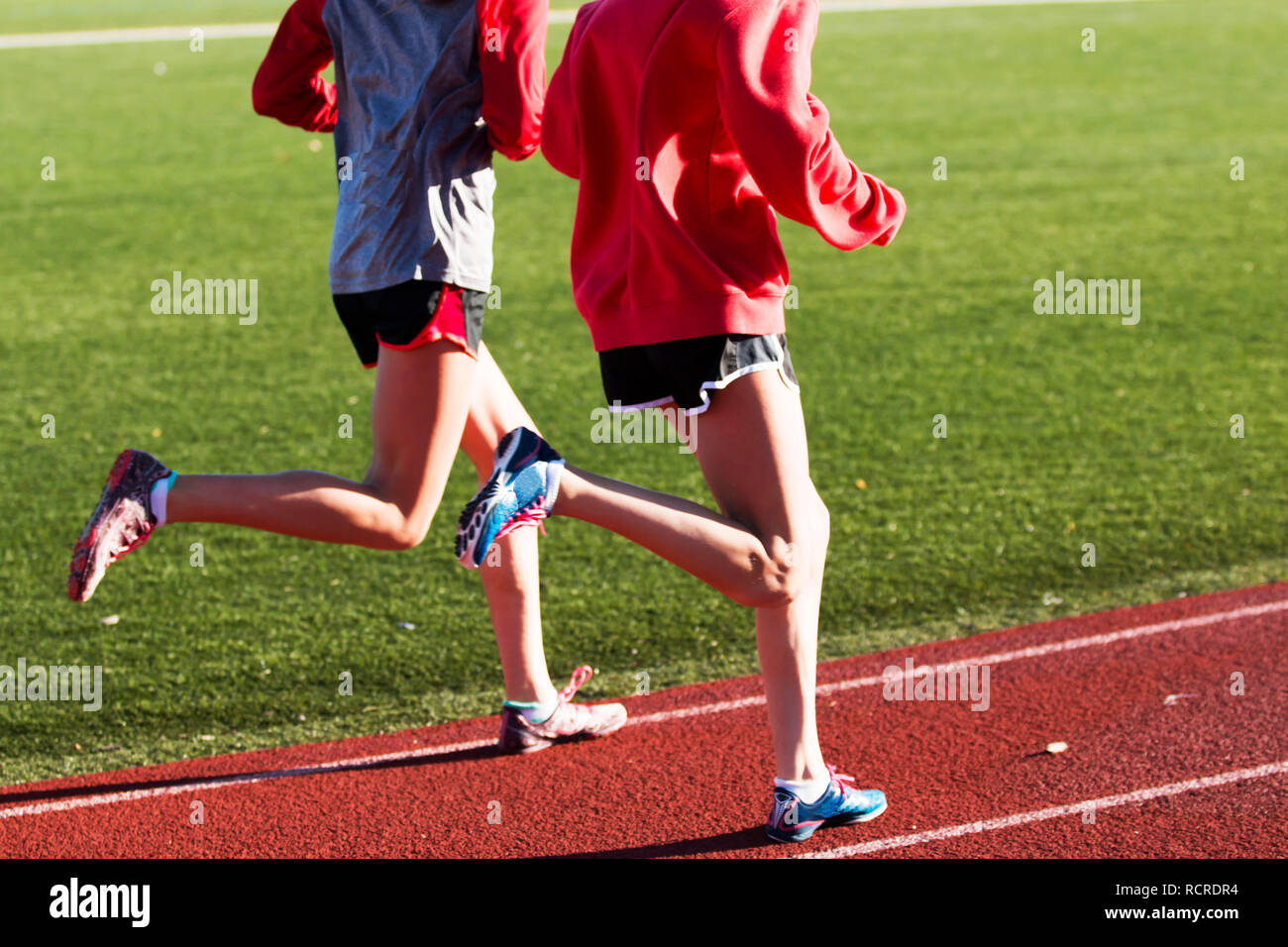 Two girls train for racing on a red track Stock Photo - Alamy
