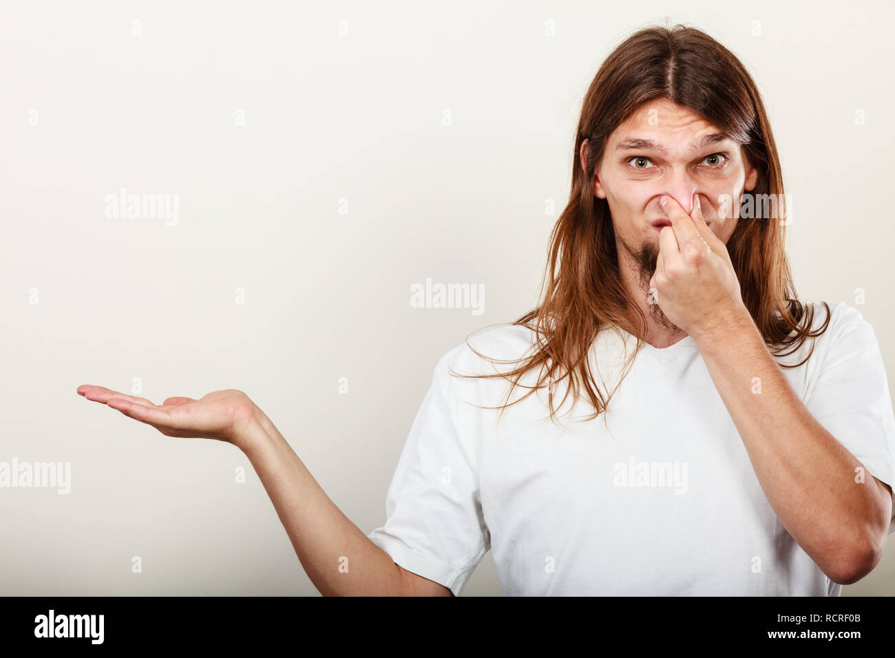 Expression of very bad smell. Young long haired sweaty man making hand ...
