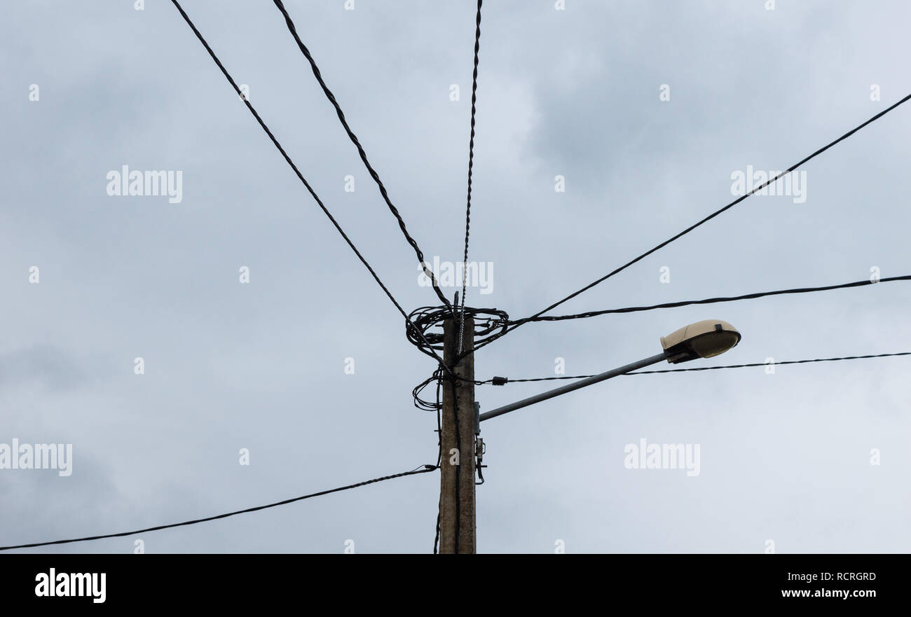 Electric pole with many cables of electric lines and a street lamp ...