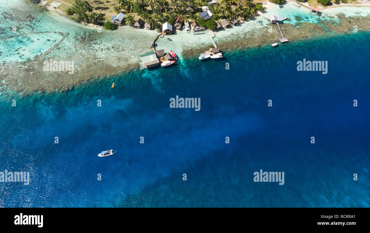 Aerial view of dinghy boat and overwater houses in the south pass of ...