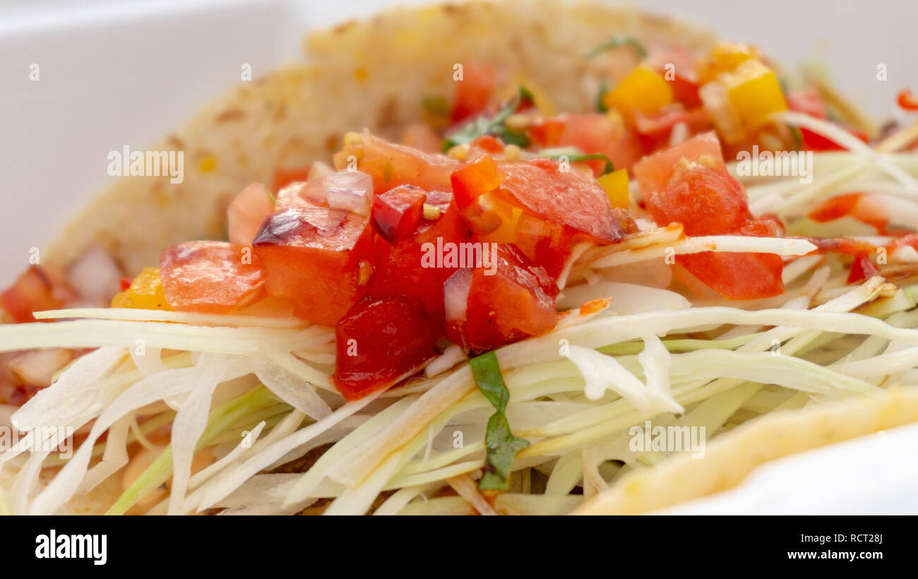 A soft taco shell with cabbage slaw and colorful red and orange pico de ...