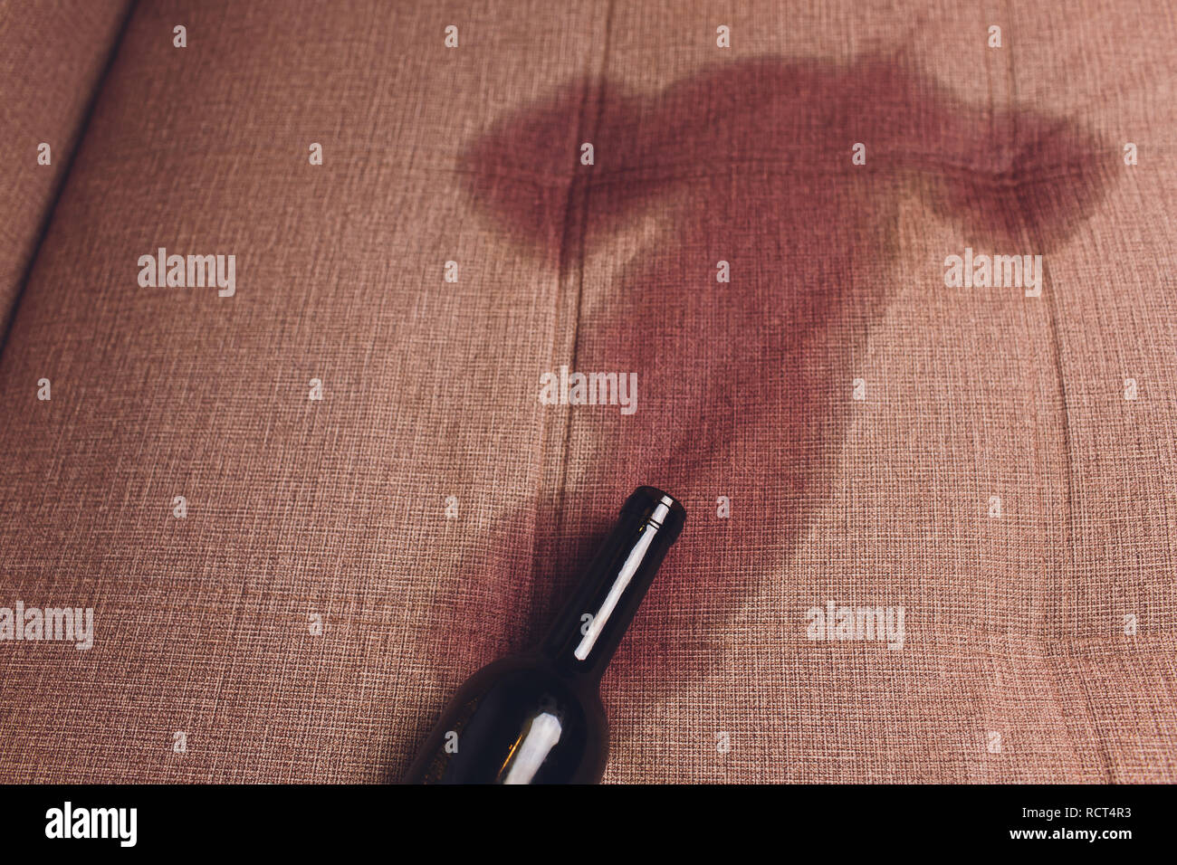 Red wine spilled on a brown couch sofa. dark bottle of red wine dropped ...