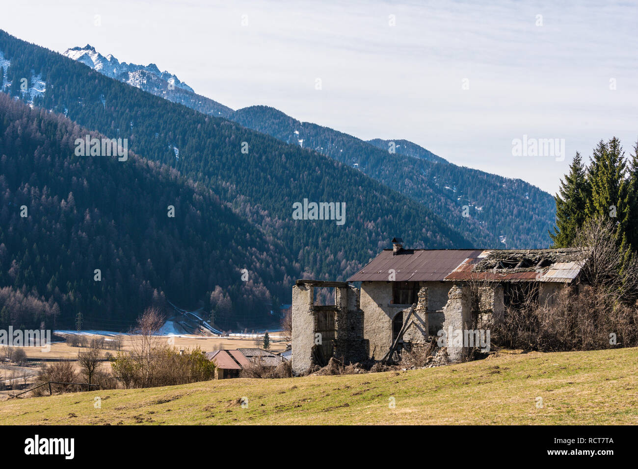 Abandoned, ruined house in Italian Alps, hills, trees, snow-capped ...