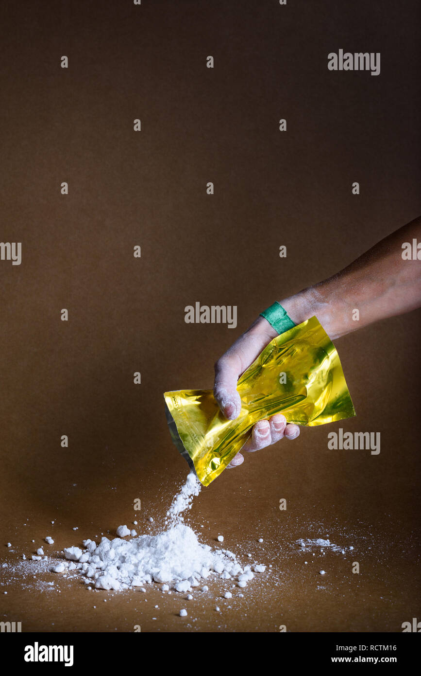 Taped hands of gymnast pouring white chalk powder into a pile. Sport ...
