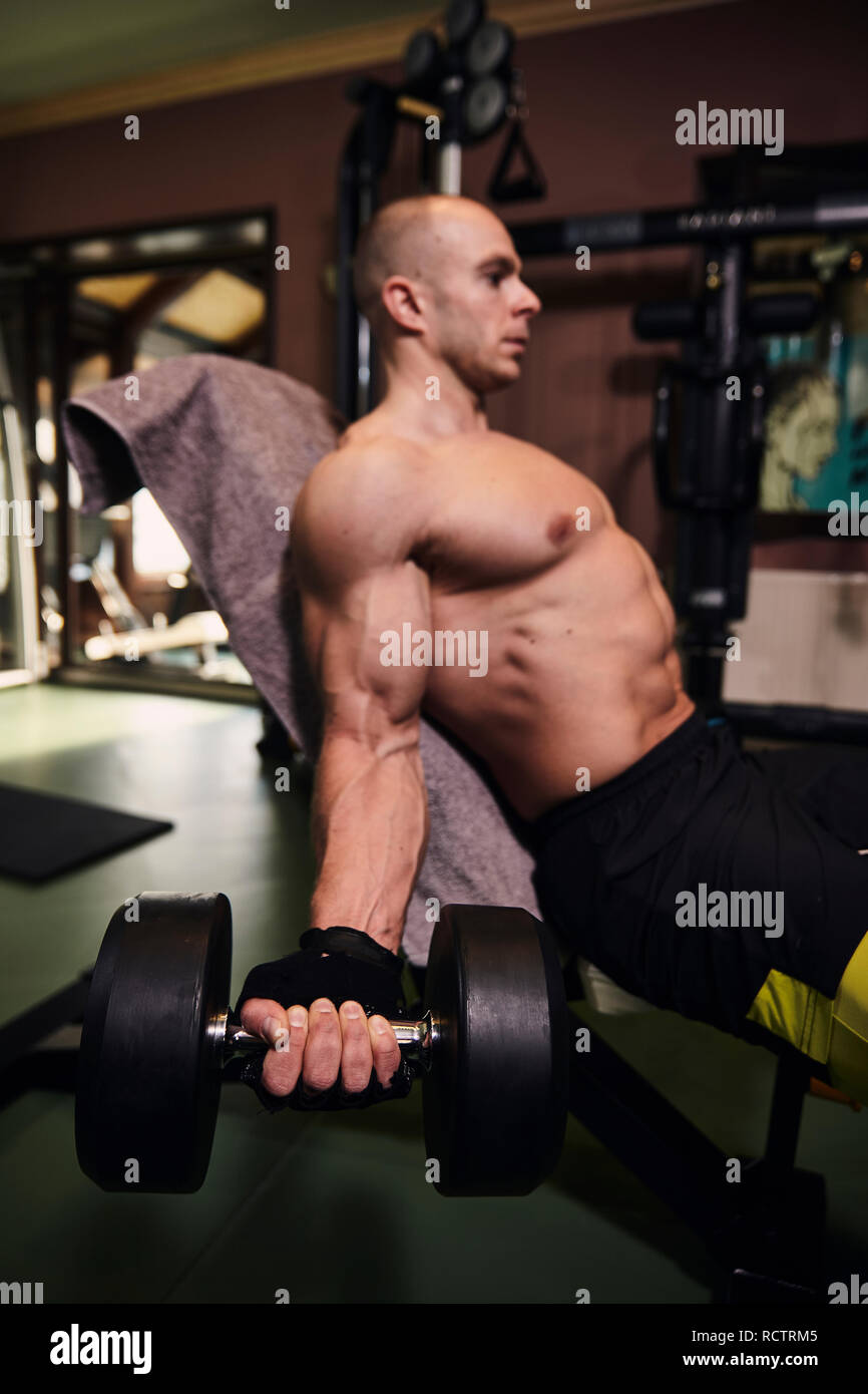 One man, bodybuilder holding dumbbell in hand which is in focus ...