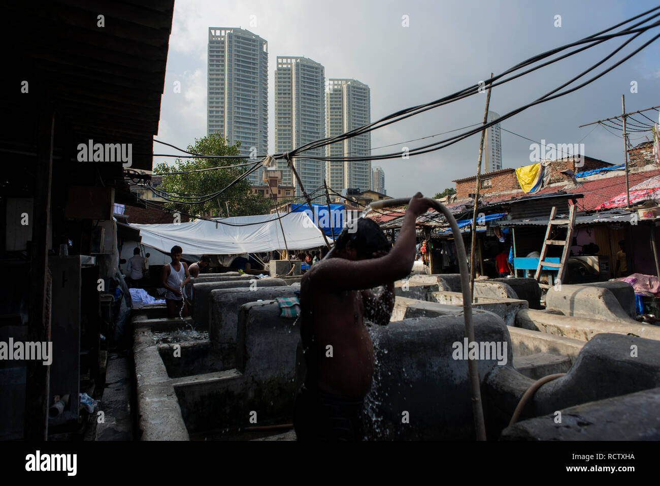 A washerman washes himself after work in an open-air laundromat in ...