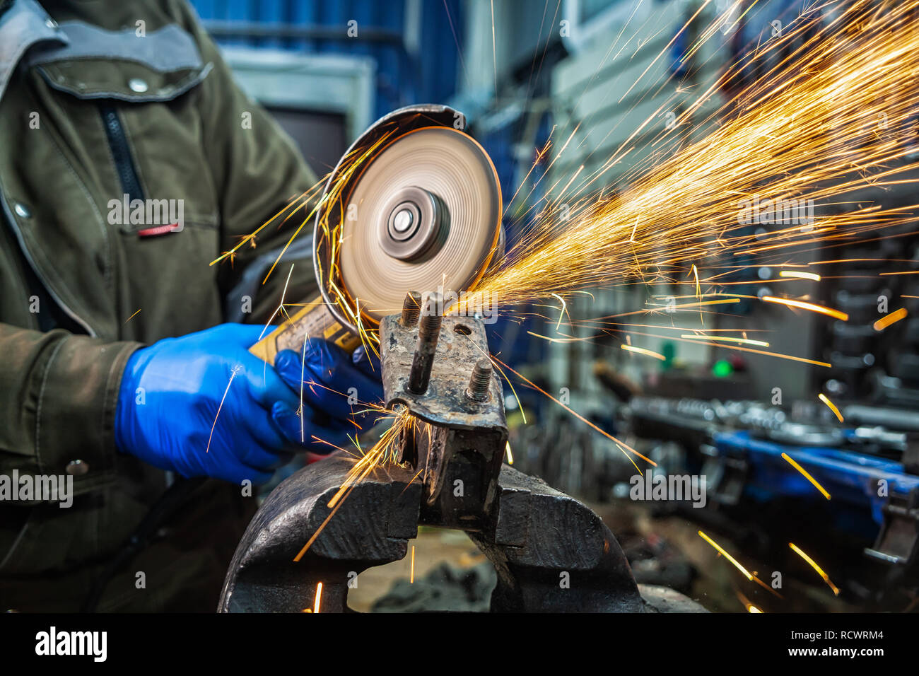 A close-up of a car mechanic using a metal grinder to cut a car silent ...