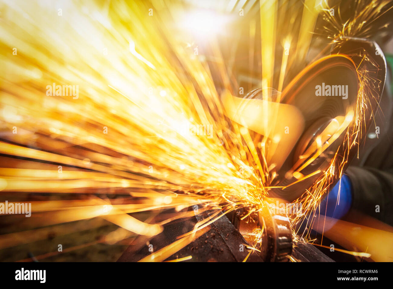 A close-up of a car mechanic using a metal grinder to cut bearing in an ...