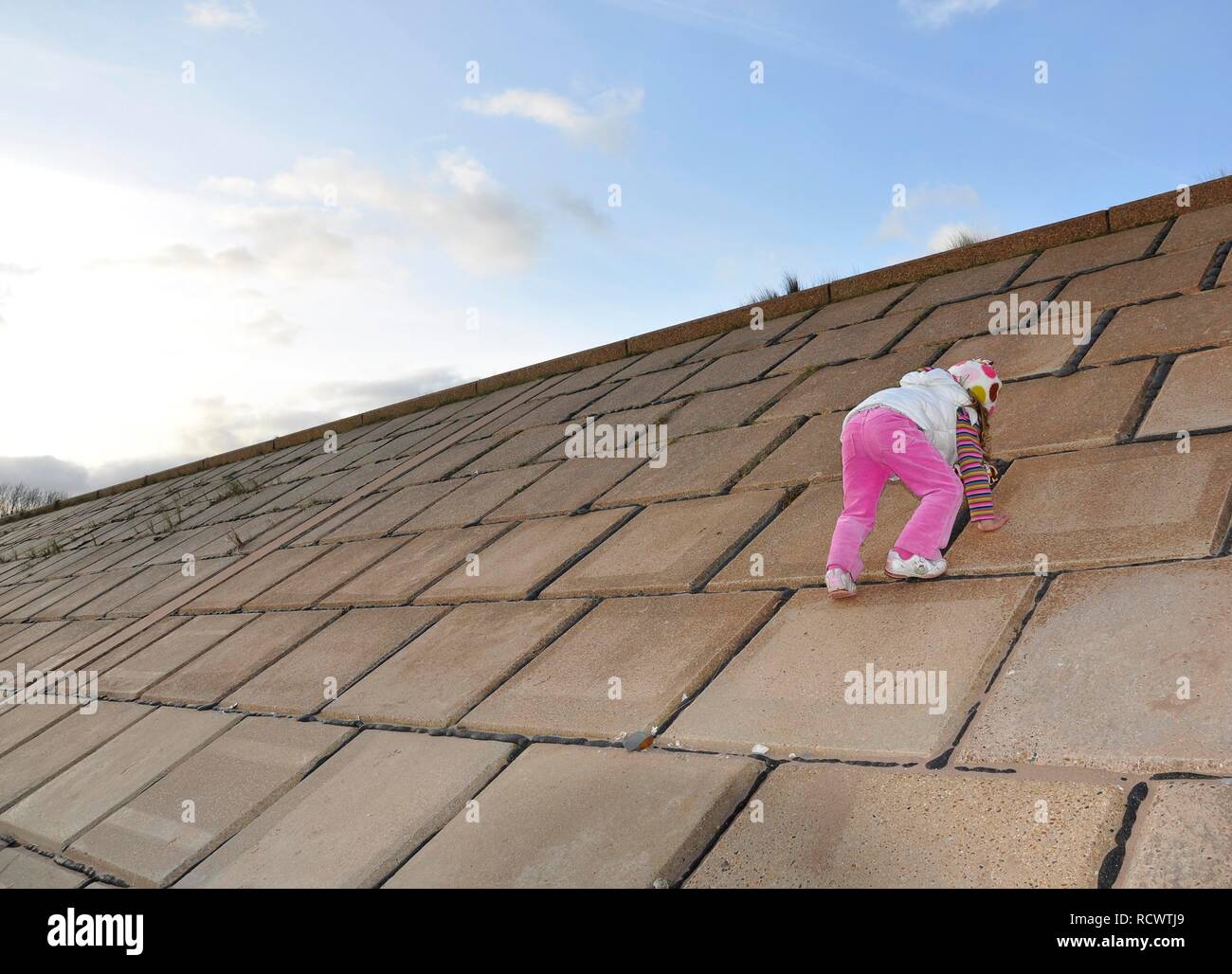 Young girl, 5 years, climbing up a steep concrete slope Stock Photo - Alamy