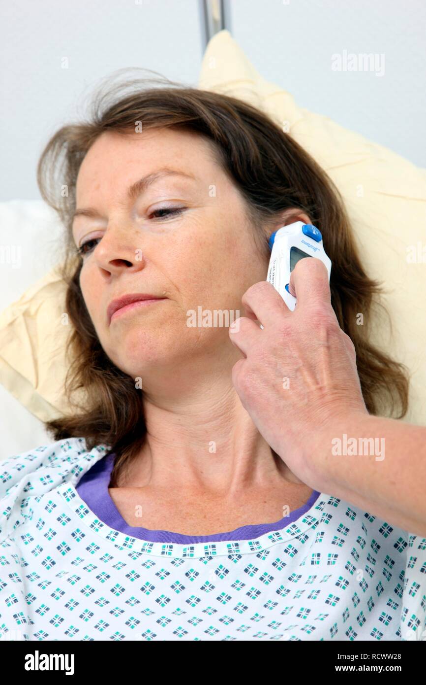 Nurse using a digital thermometer to measure the body temperature of a ...